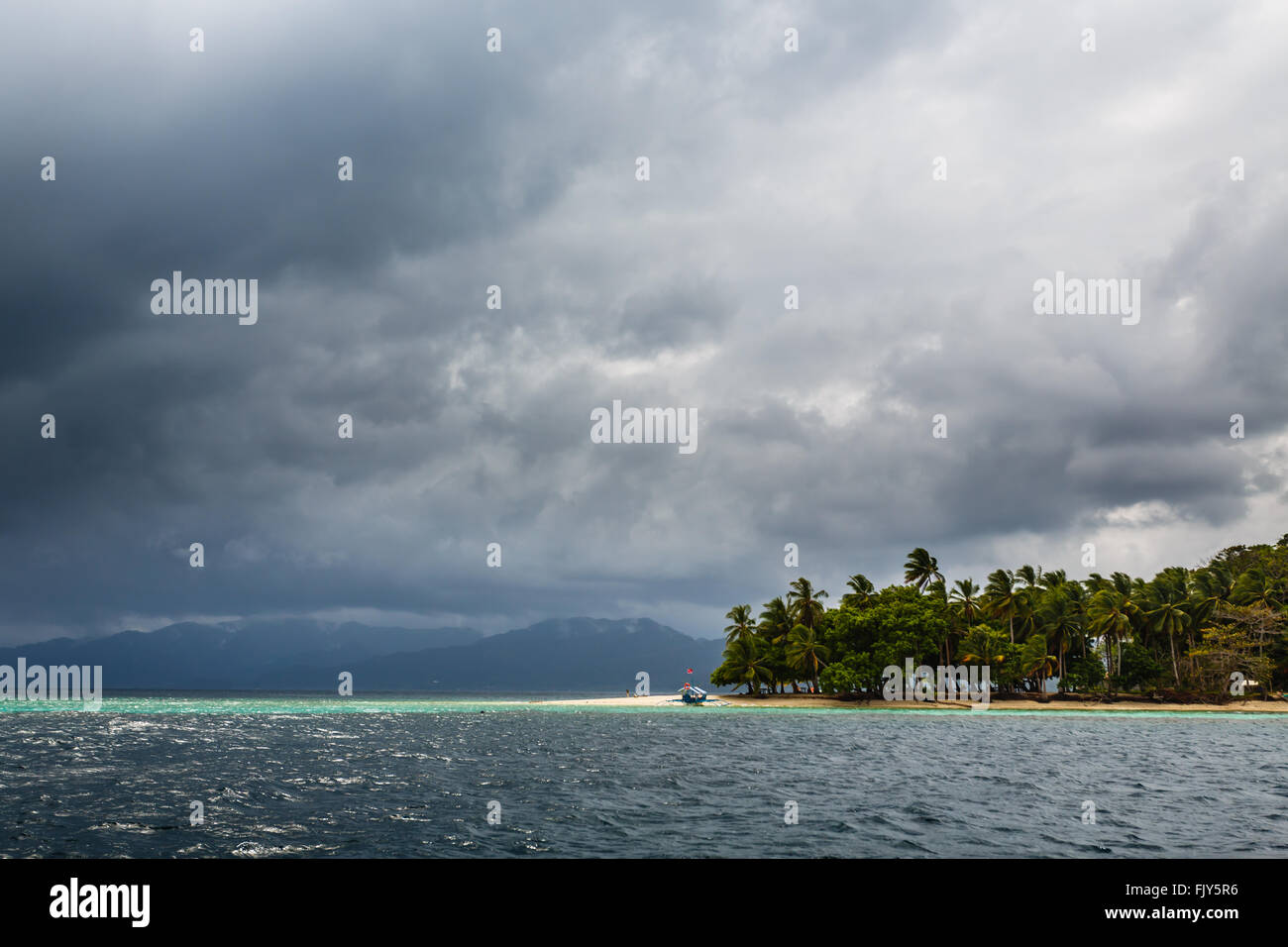 Storm clouds closing in on tropical island view of boat and palms ...