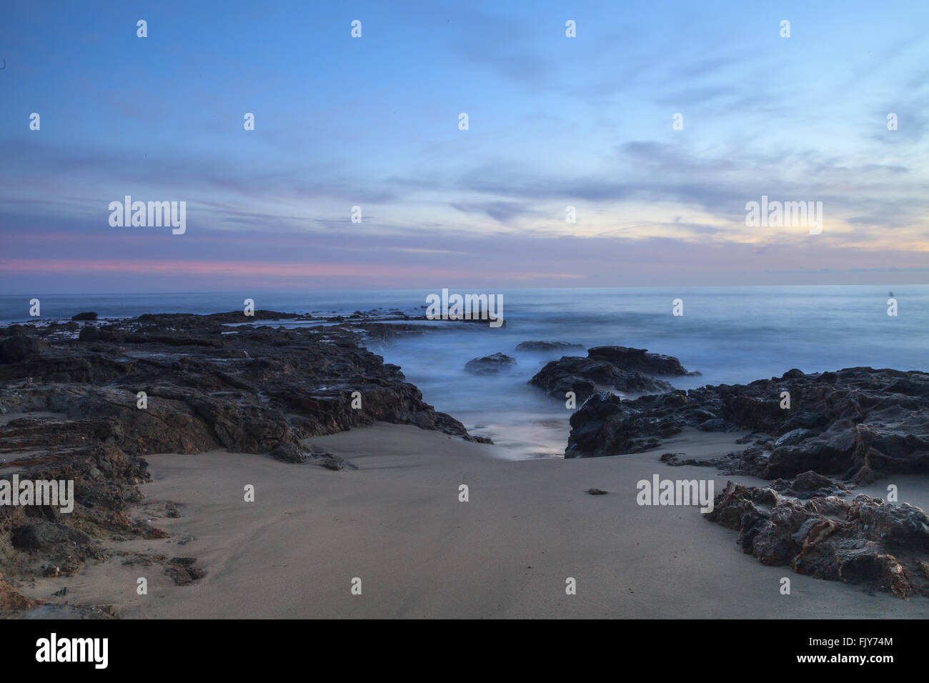 Long exposure of sunset over rocks, giving a mist like effect over ...