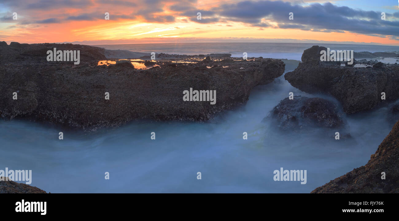 Long exposure of sunset over rocks, giving a mist like effect over ...