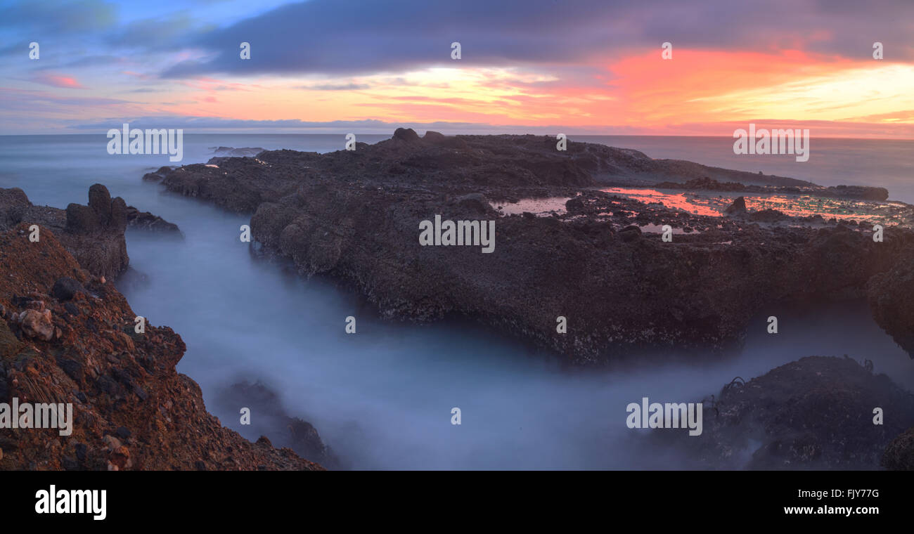 Long exposure of sunset over rocks, giving a mist like effect over ...
