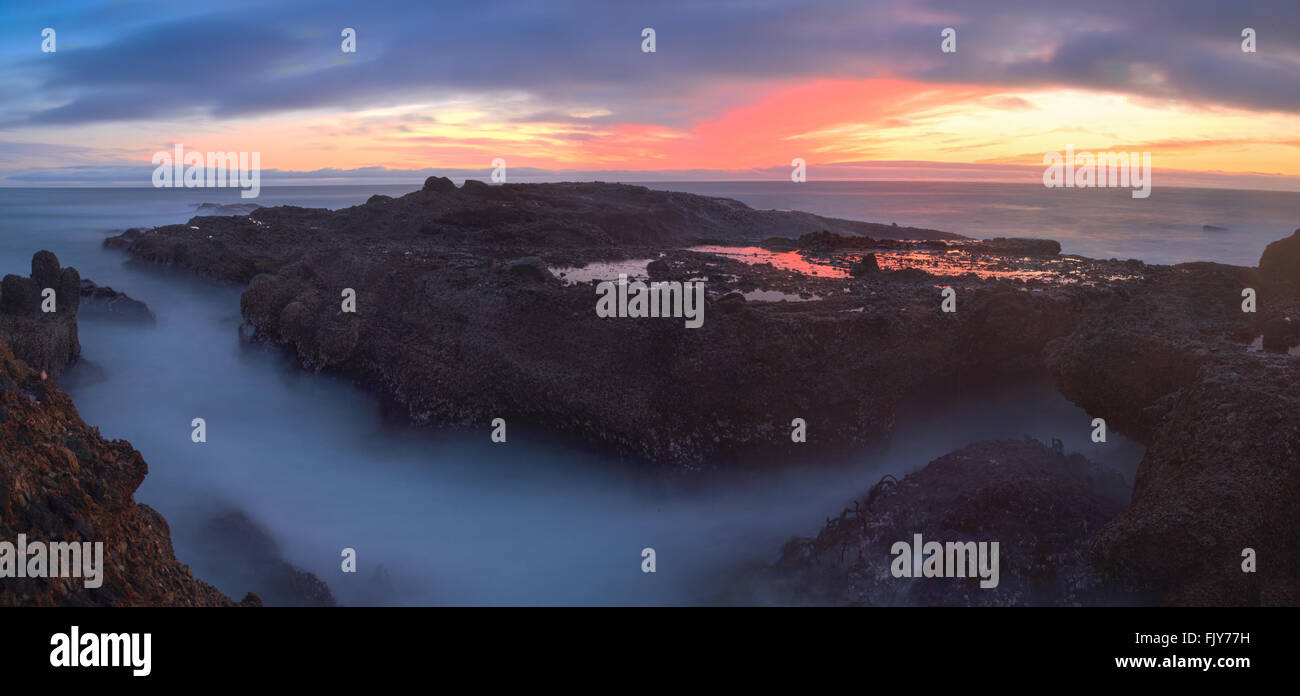Long exposure of sunset over rocks, giving a mist like effect over ...