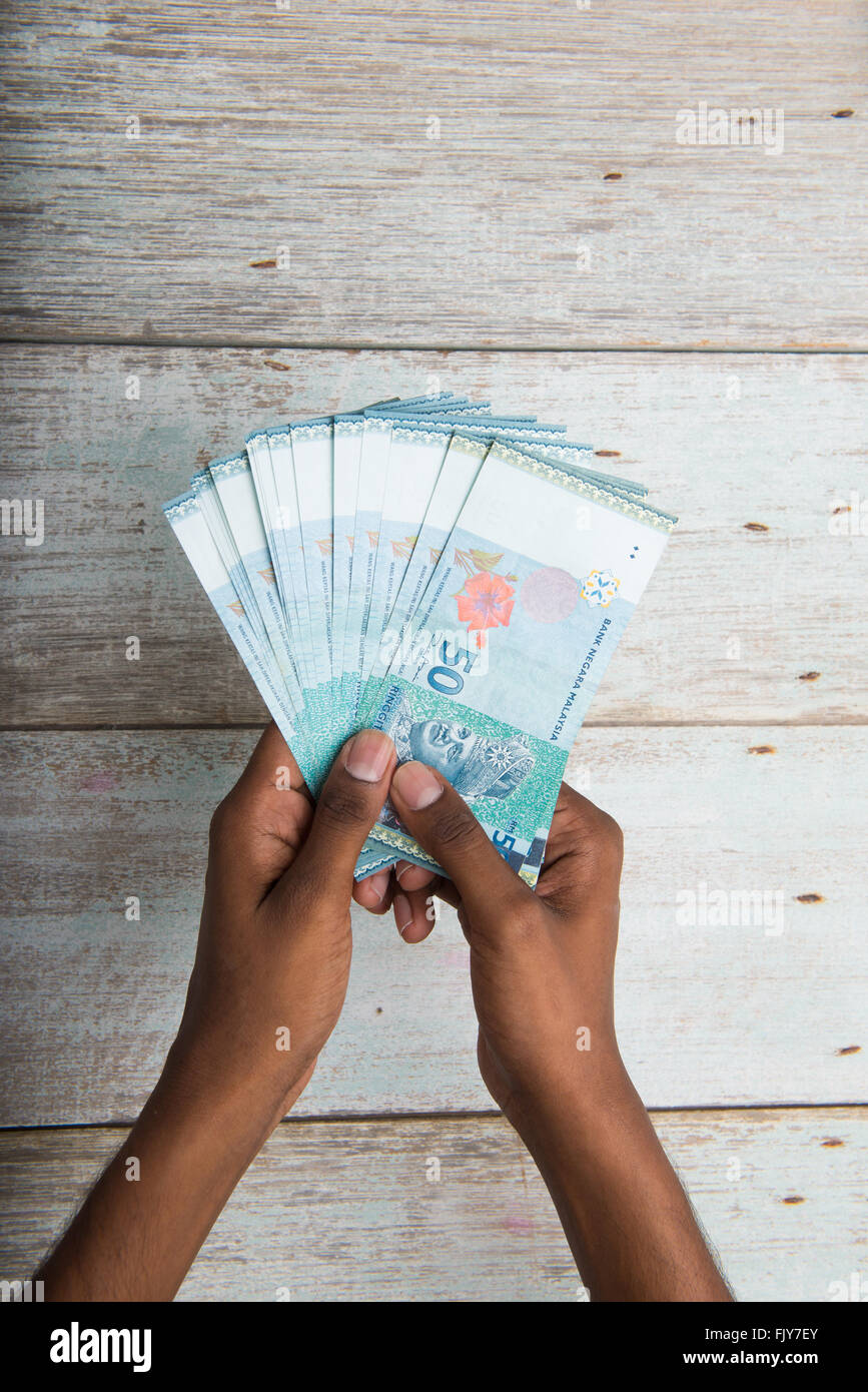 Handing out money in Malaysia ringgit , dark tone skin Stock Photo - Alamy