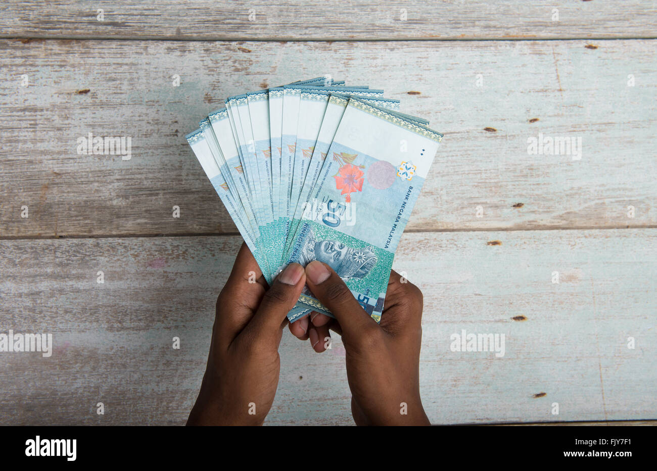 Handing out money in Malaysia ringgit , dark tone skin Stock Photo - Alamy