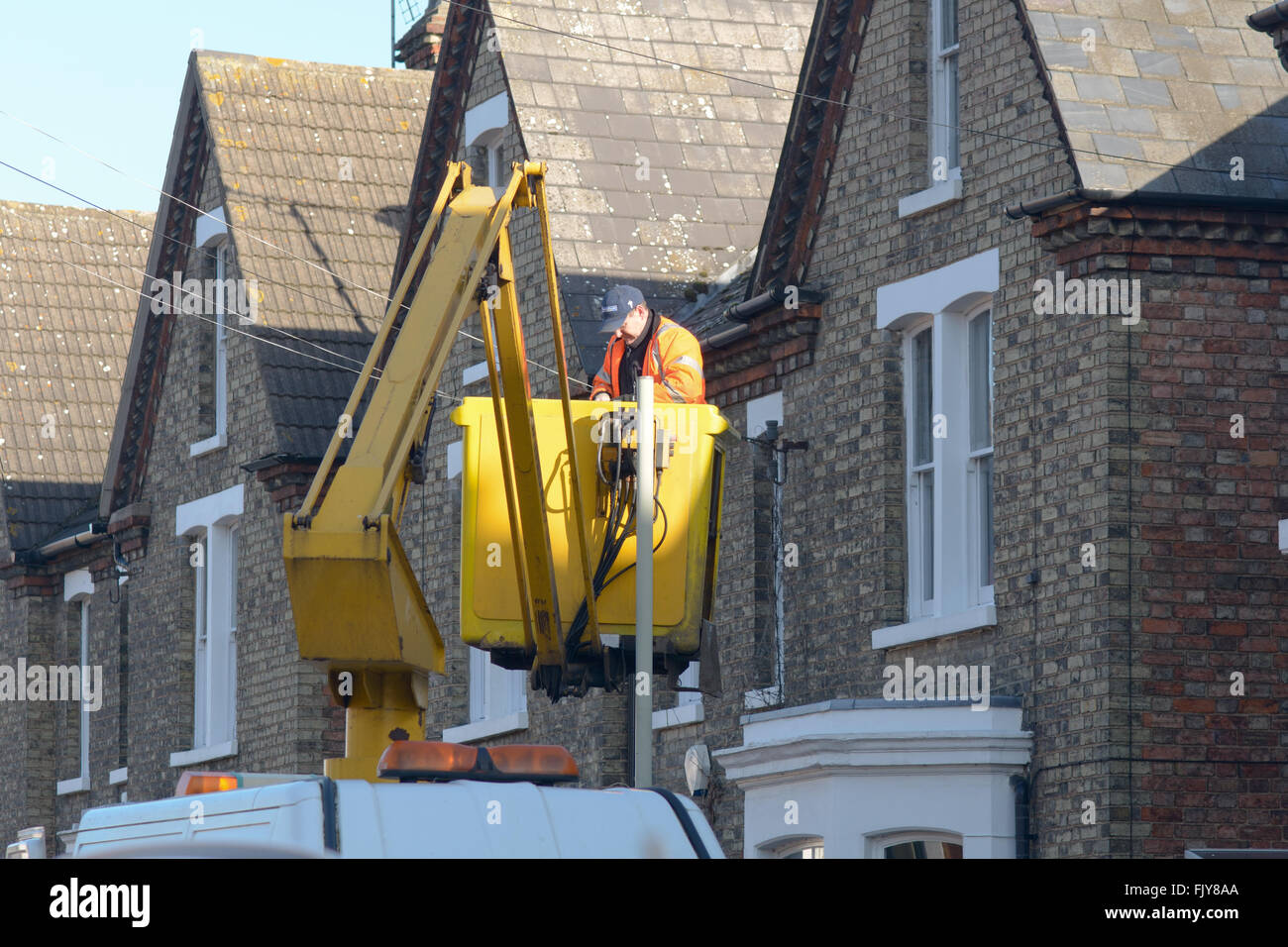 Workman replacing a lamp post light in a cherry picker boom lift in ...