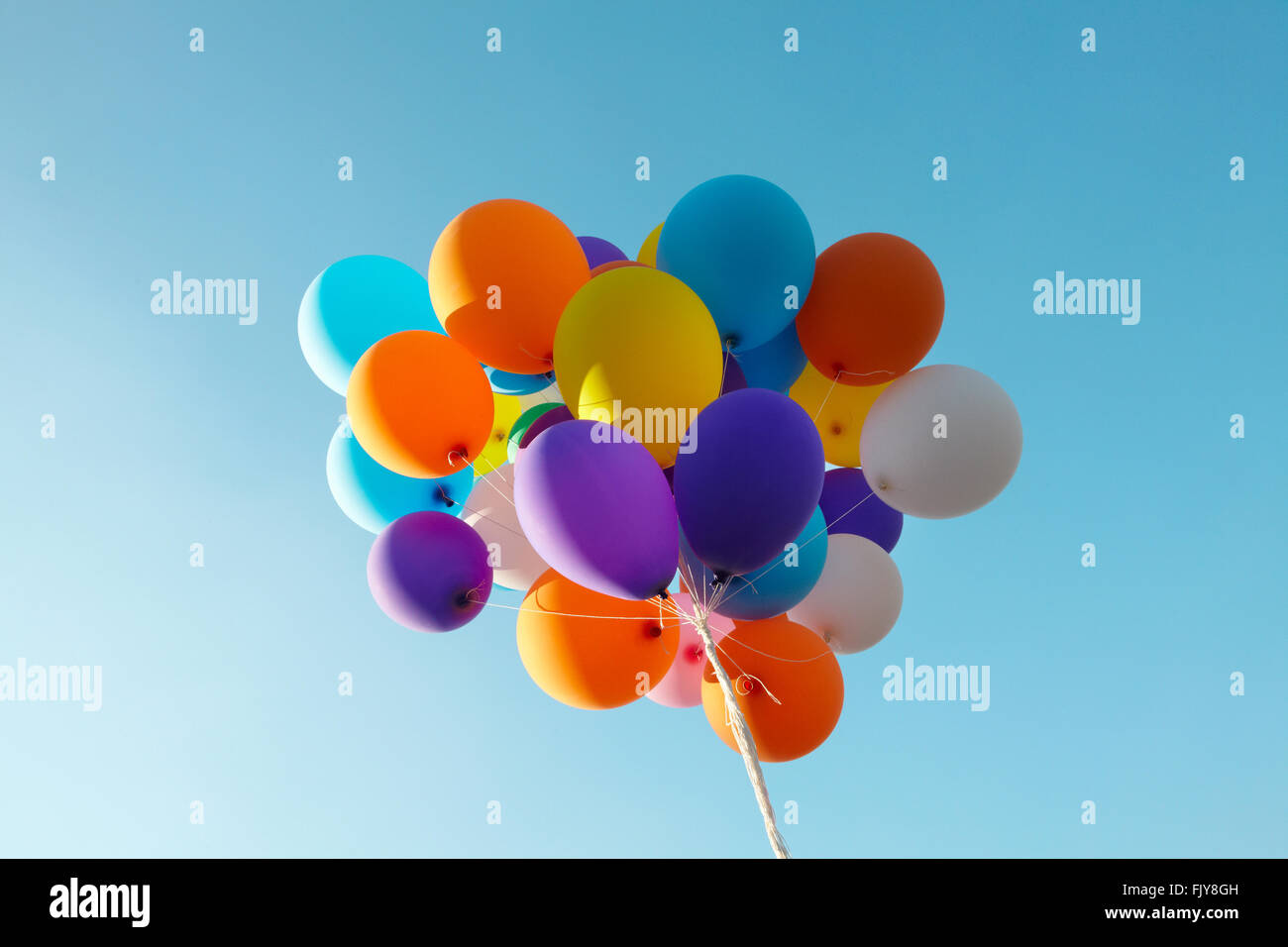 A multicolored balloon bunch in a blue sky. Horizontal Stock Photo - Alamy