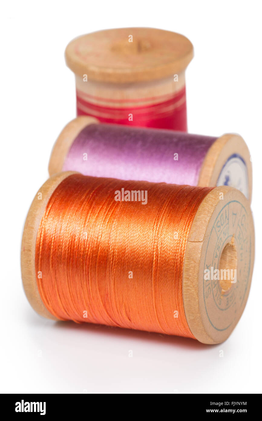 Three colorful spools of orange, purple and red nylon thread on white ...