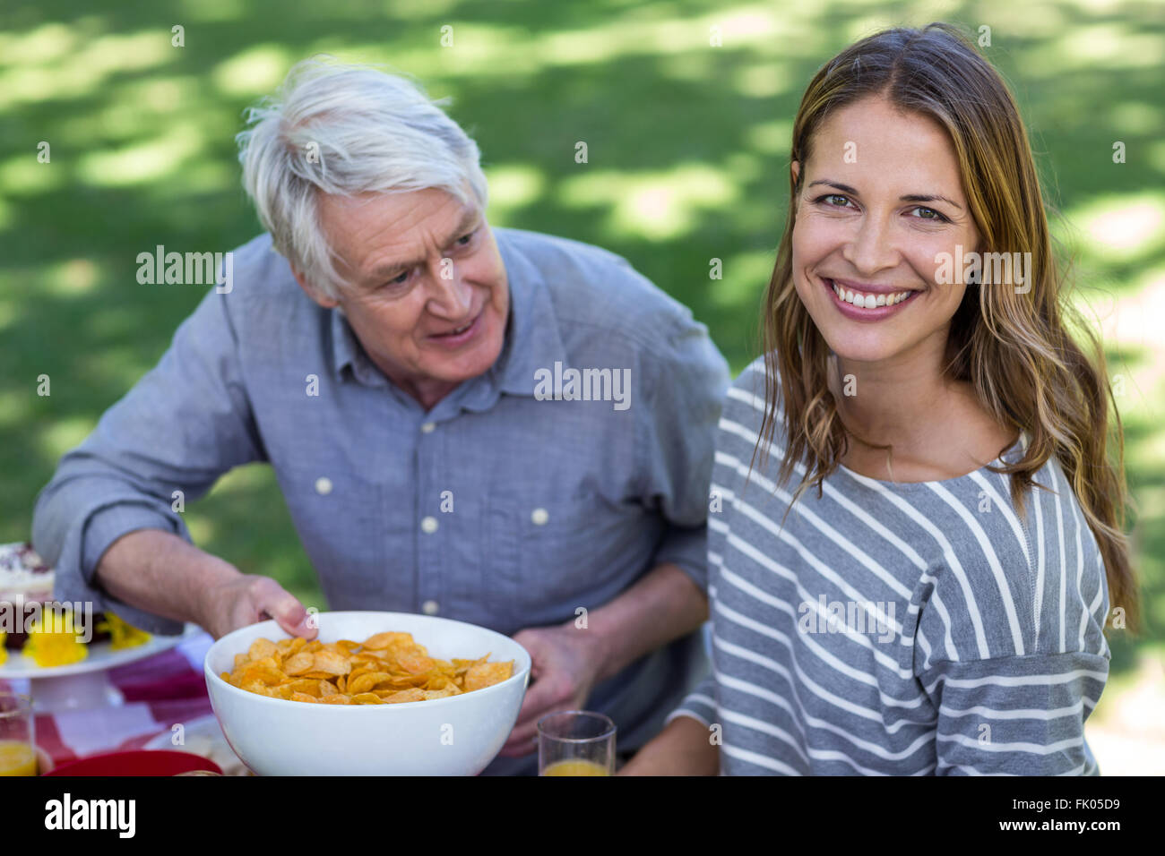 Senior man offering crisps to young woman Stock Photo - Alamy