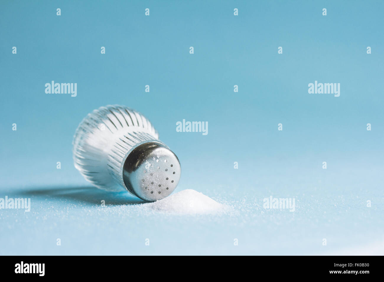 Spilled salt and saltshaker on blue background Stock Photo - Alamy