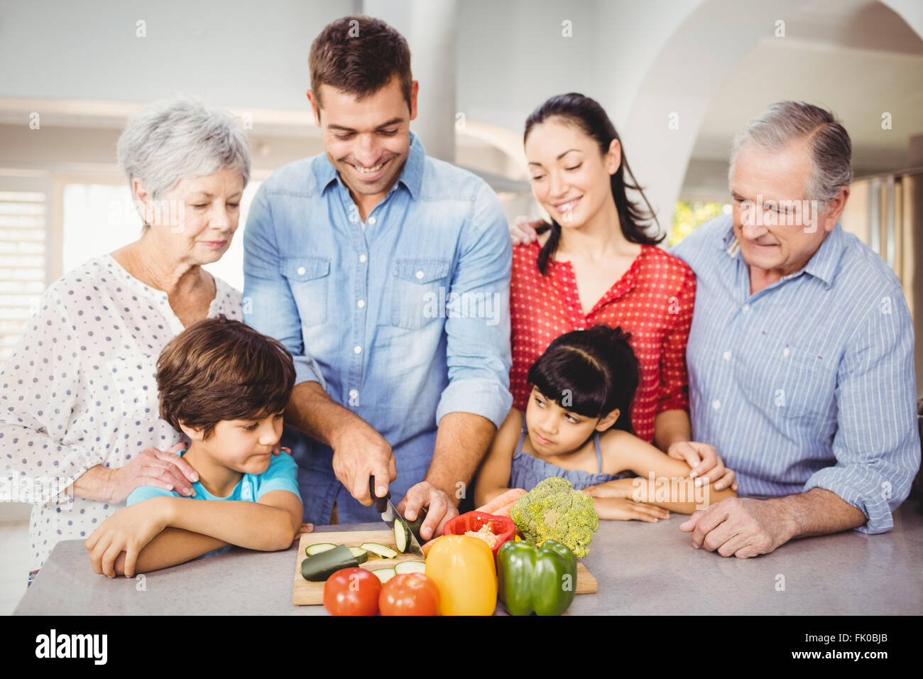 Happy man with family by kitchen table Stock Photo - Alamy