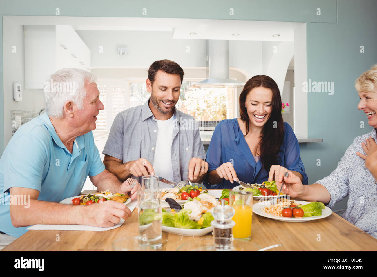 Family laughing while sitting at dining table Stock Photo - Alamy