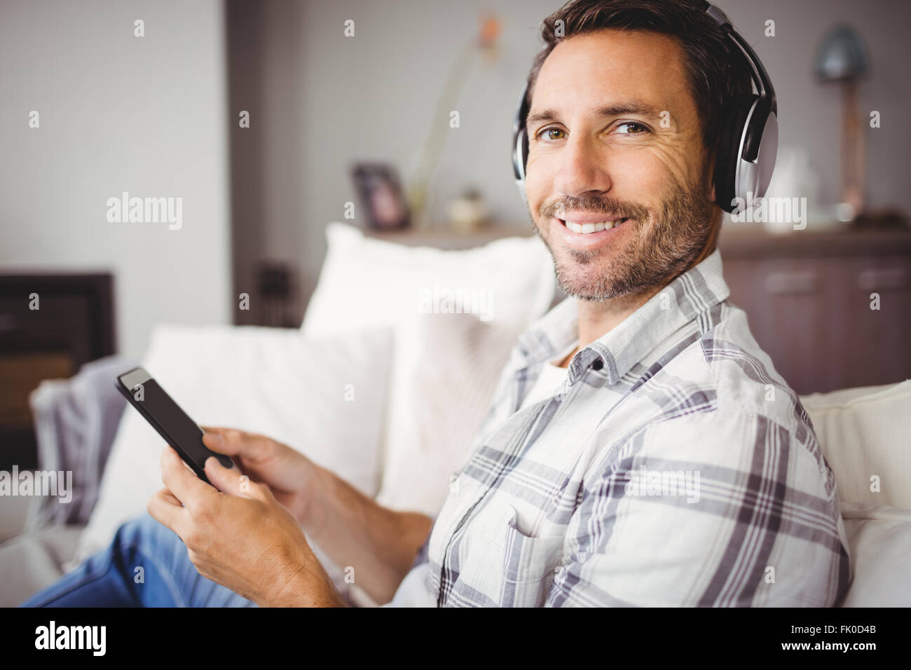 Portrait of man wearing headphones while using mobile phone Stock Photo ...