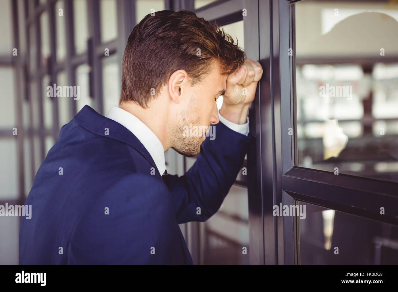 Tired businessman leaning on door Stock Photo - Alamy