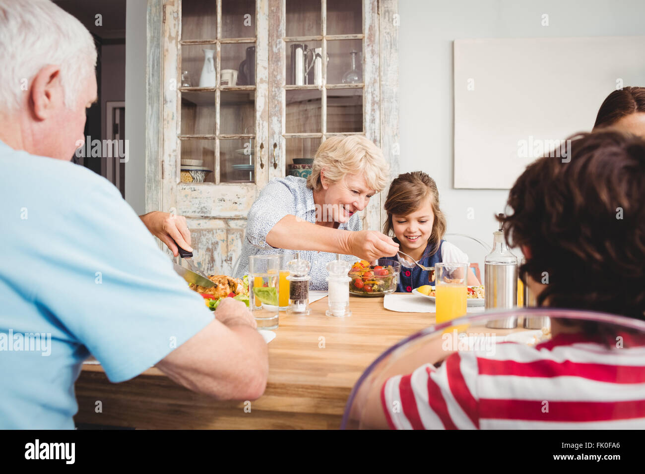 Smiling granny and granddaughter while sitting at dining table Stock ...