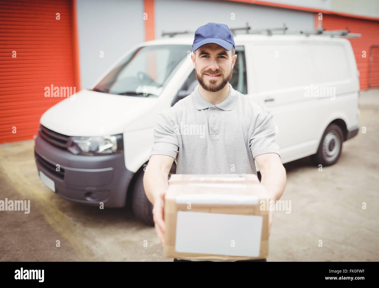 Delivery man holding package Stock Photo - Alamy