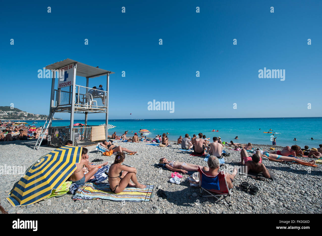 The beach at Nice in summer, busy with sunbathers and swimmers Stock ...