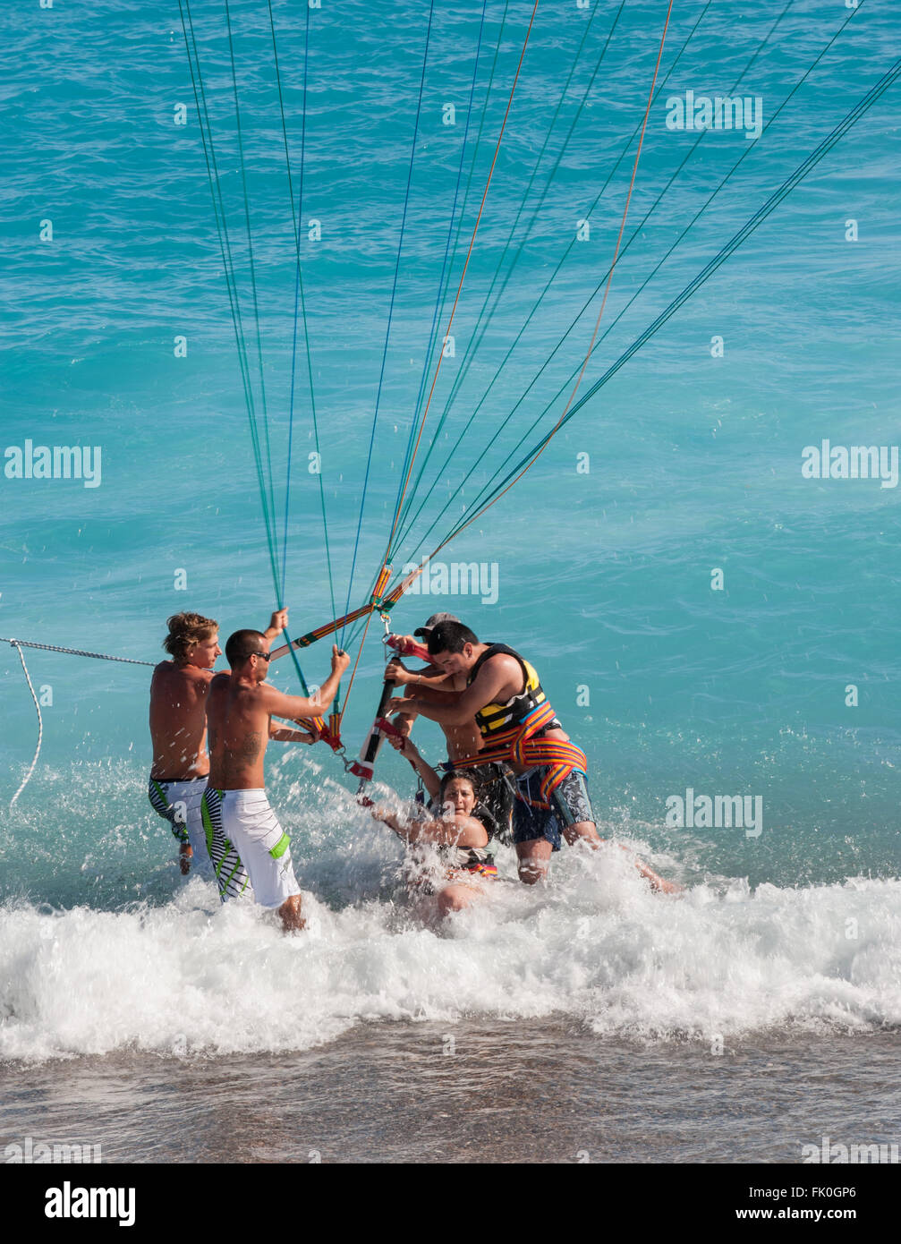 A para glider returning to the beach struggling in the surf to remove ...