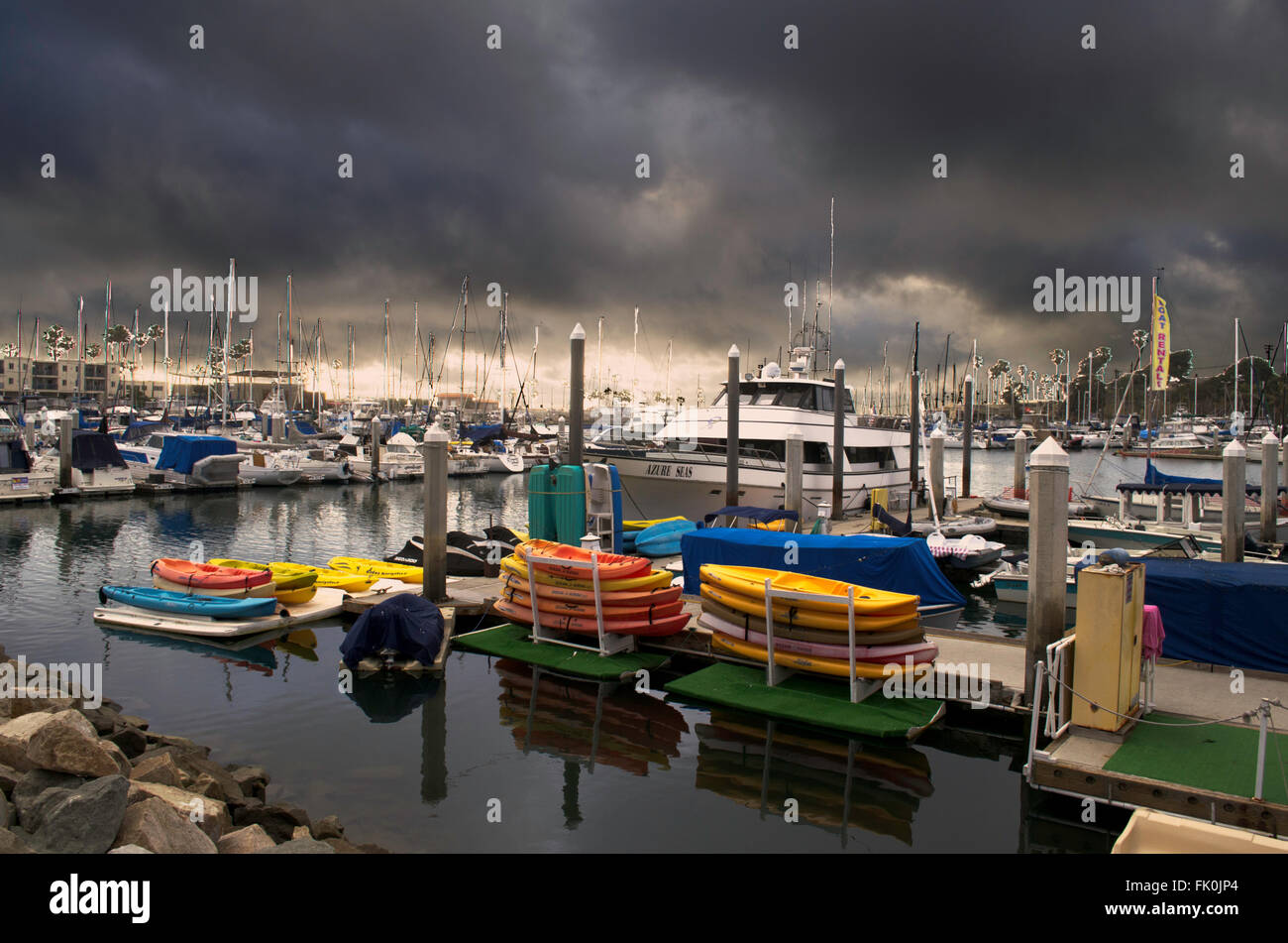 Storm clouds over harbor, boats docked, colorful rafts and kayaks ...