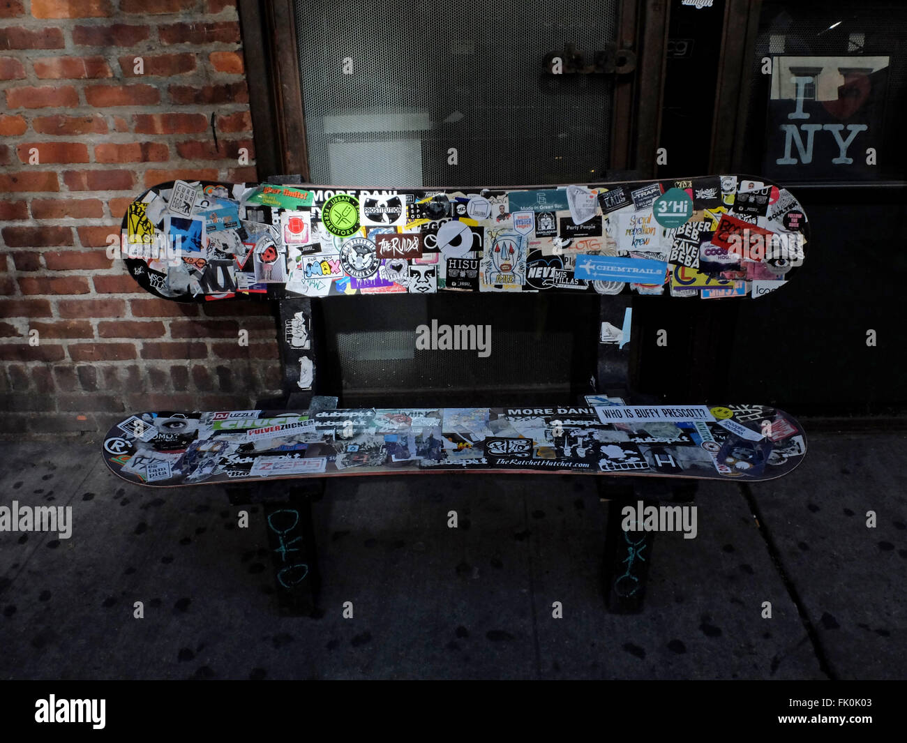A bench covered with graffiti & stickers and made of two skateboards ...