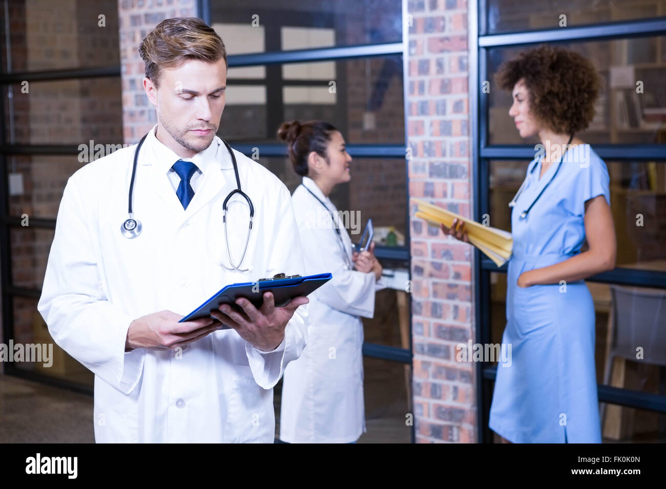 Male doctor looking at clipboard near library Stock Photo - Alamy
