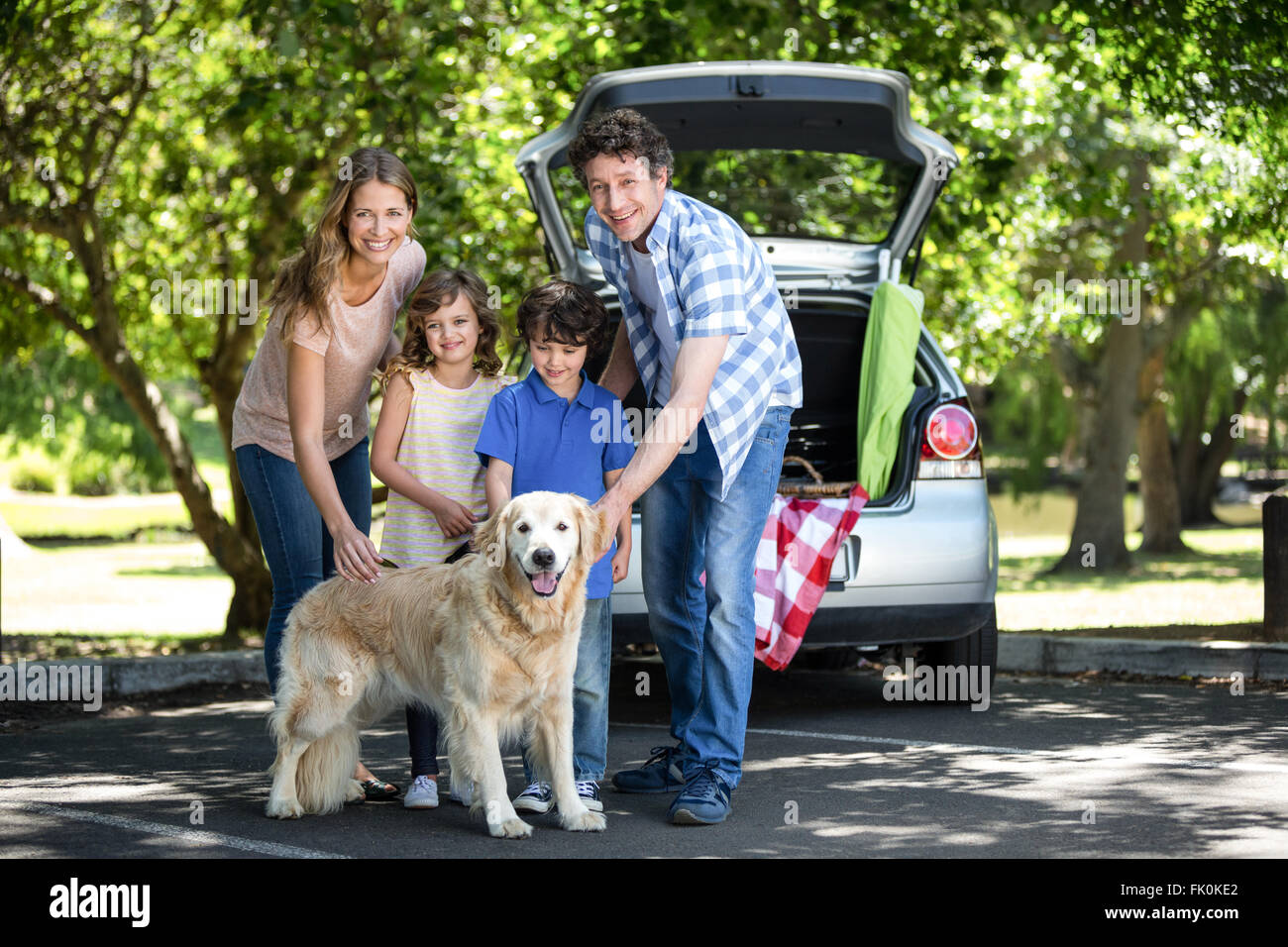 Smiling family standing in front of a car Stock Photo - Alamy