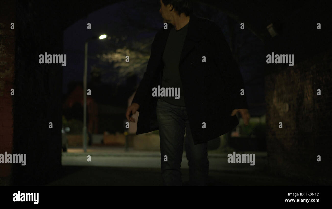 Man at night looking behind fearing he may be being followed Stock ...