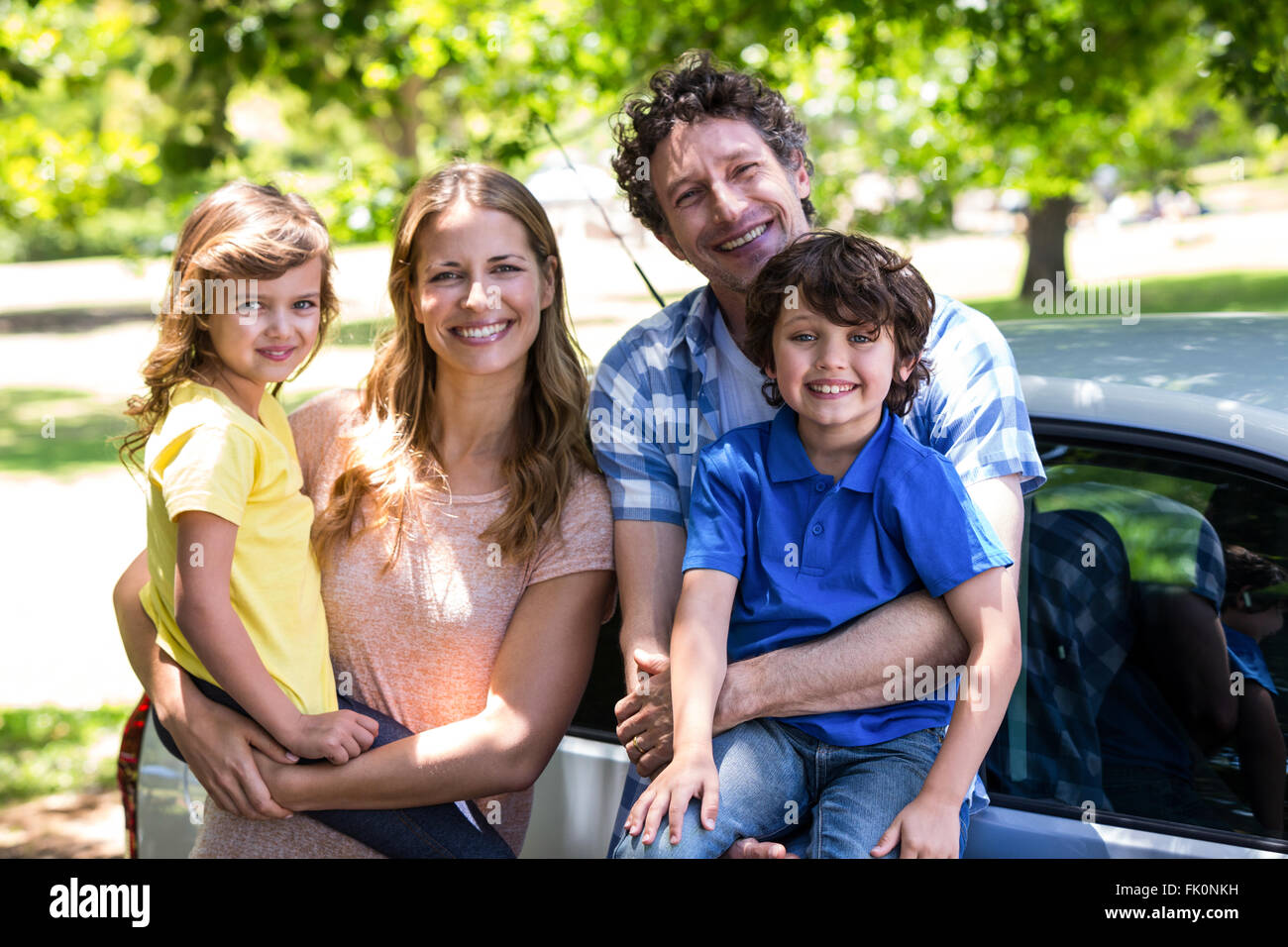 Smiling family in front of a car Stock Photo - Alamy