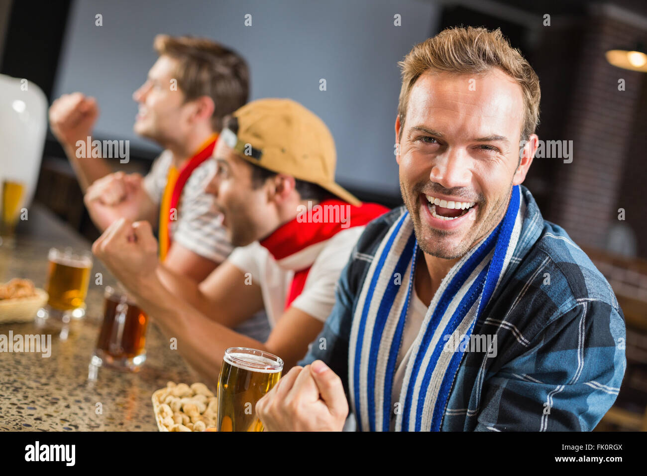 Man looking at camera while other men cheer for the game Stock Photo ...