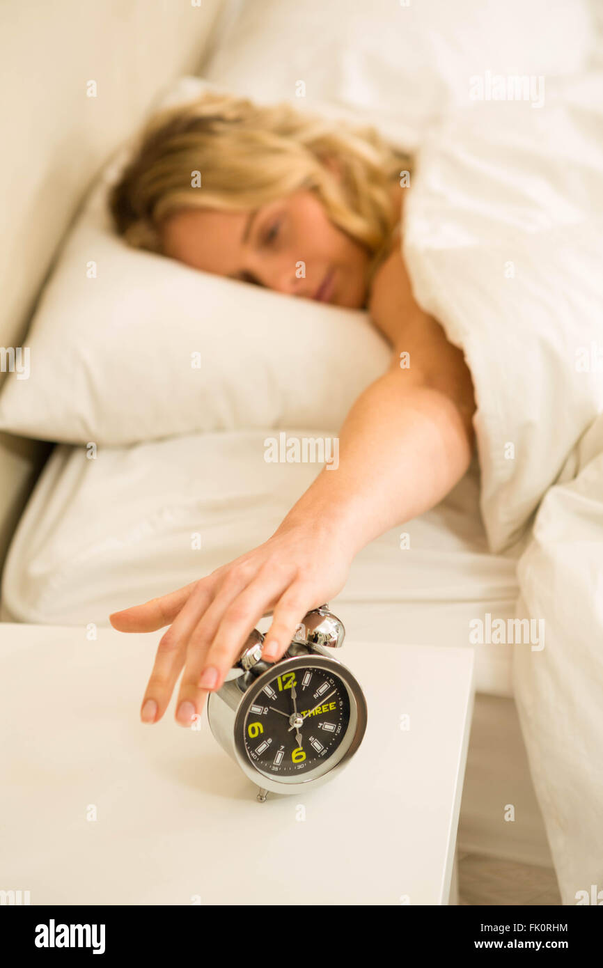 Pretty woman shutting off her alarm clock Stock Photo - Alamy