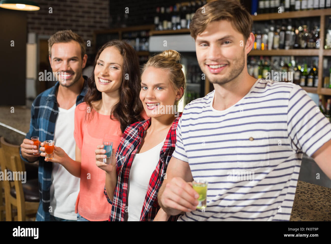 Friends looking at a camera with shots in hand Stock Photo - Alamy