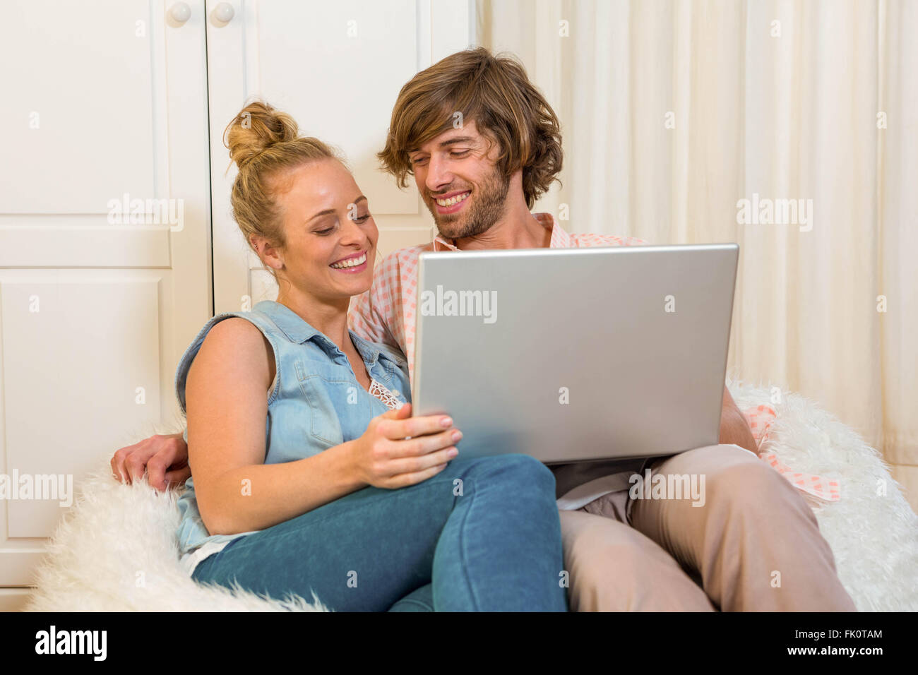 Cute couple using laptop sitting on the couch Stock Photo - Alamy