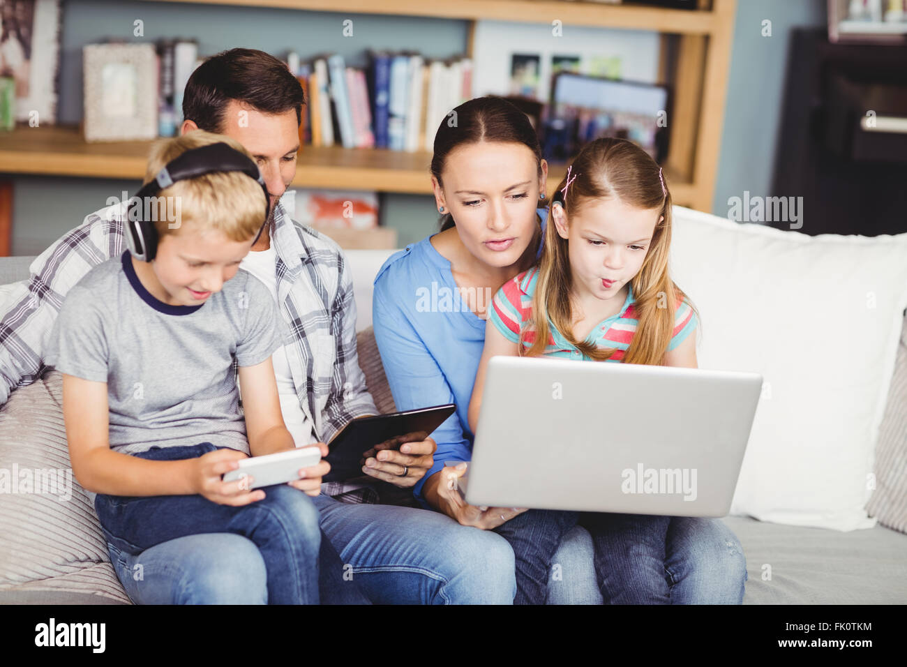 Children using technologies with parents on sofa Stock Photo - Alamy