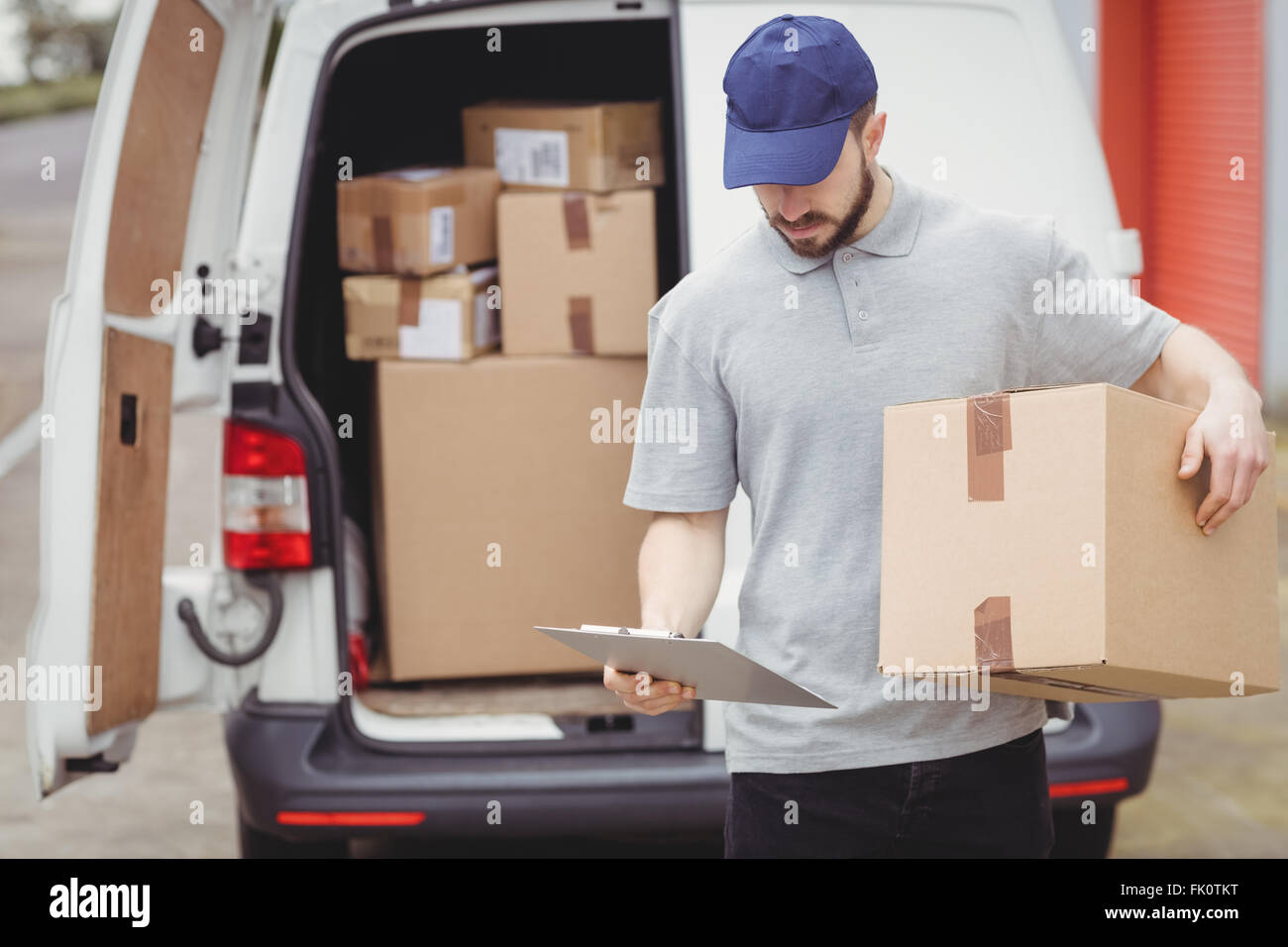 Delivery man reading notes on his clipboard Stock Photo - Alamy