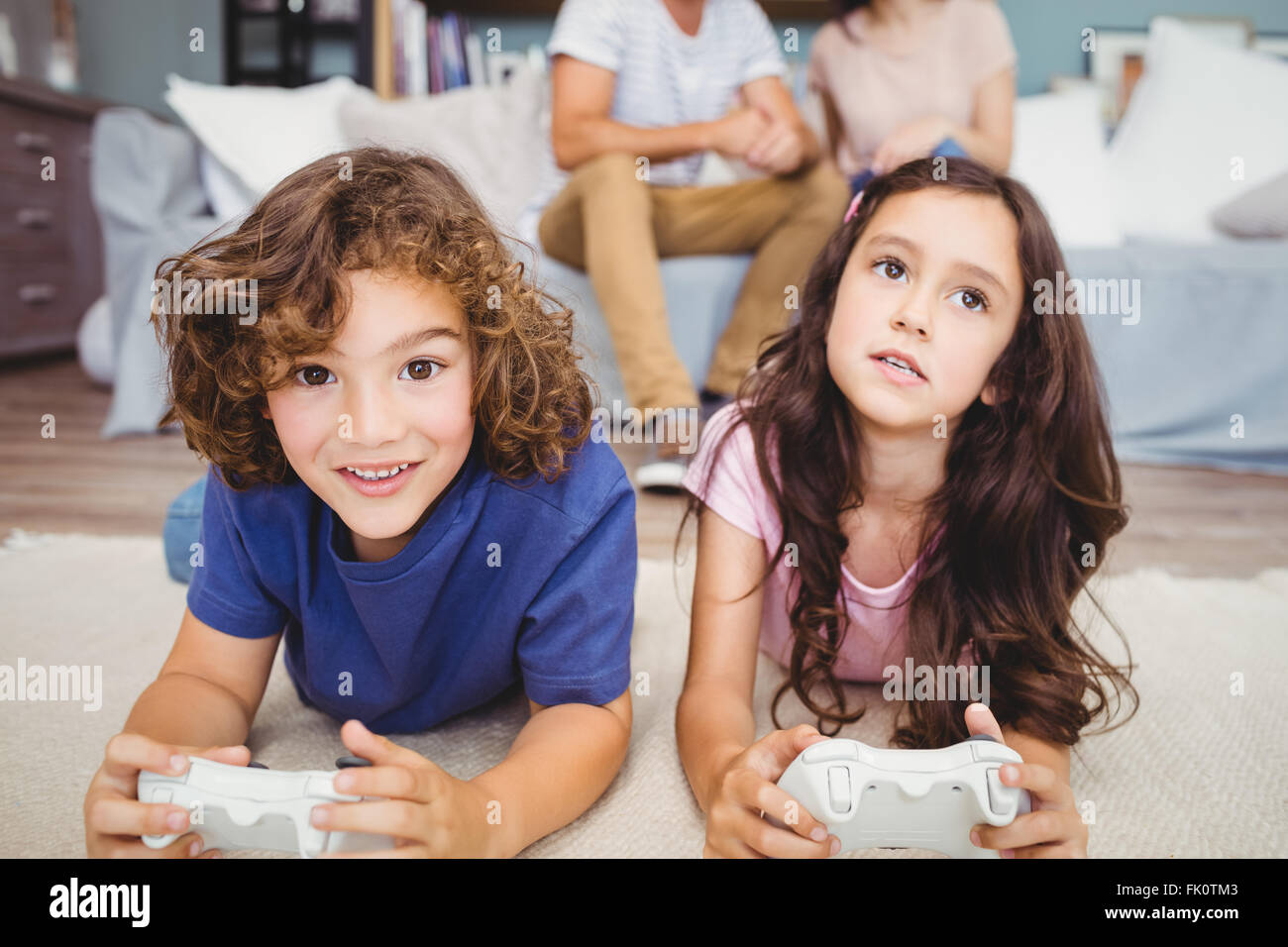Siblings with playing video game on carpet Stock Photo - Alamy