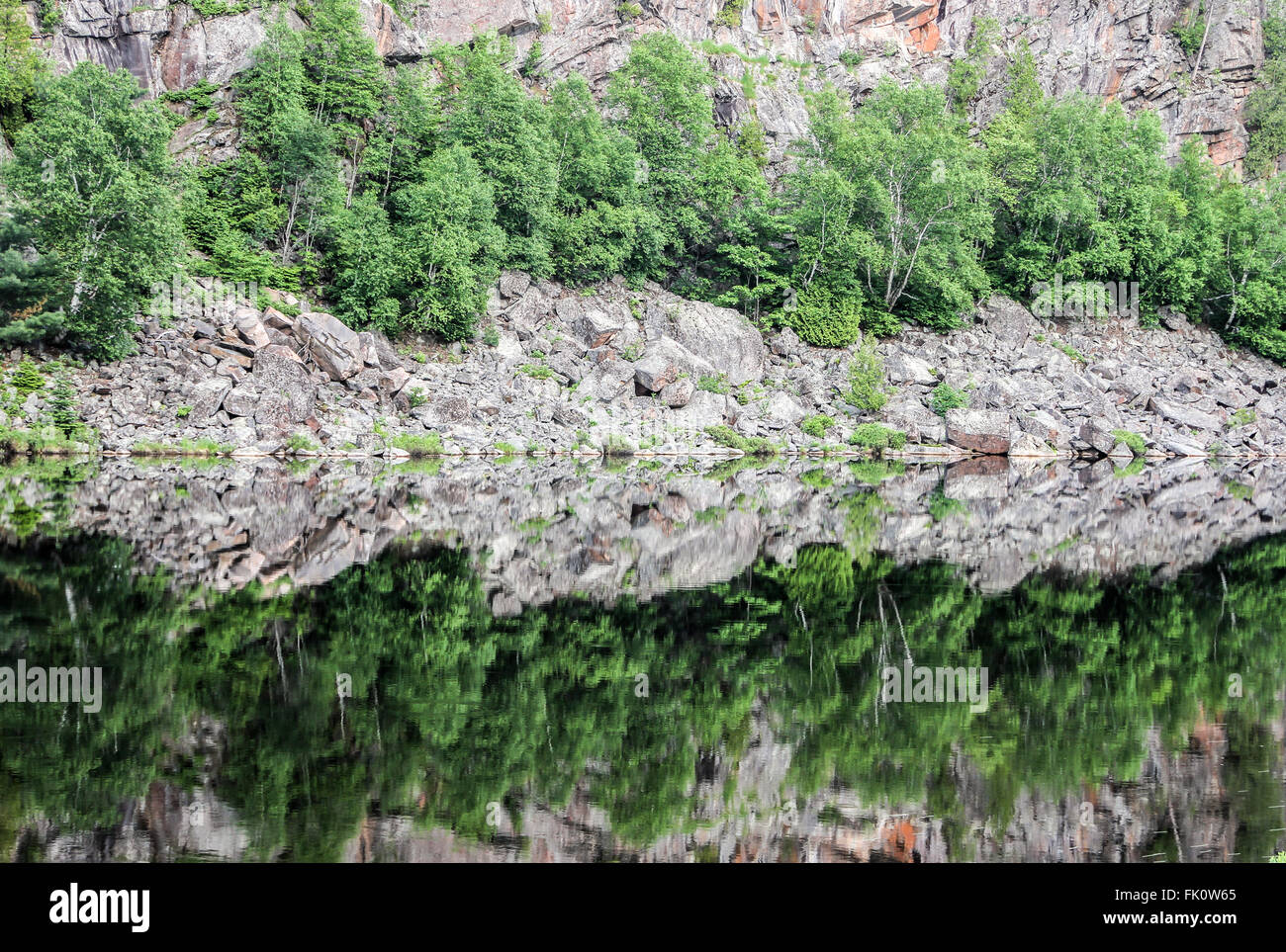 The reflection of rocks and trees in a lake Stock Photo - Alamy