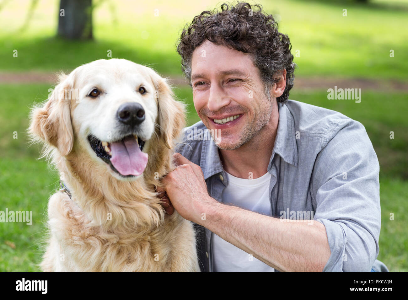 Smiling man with his dog in park Stock Photo - Alamy