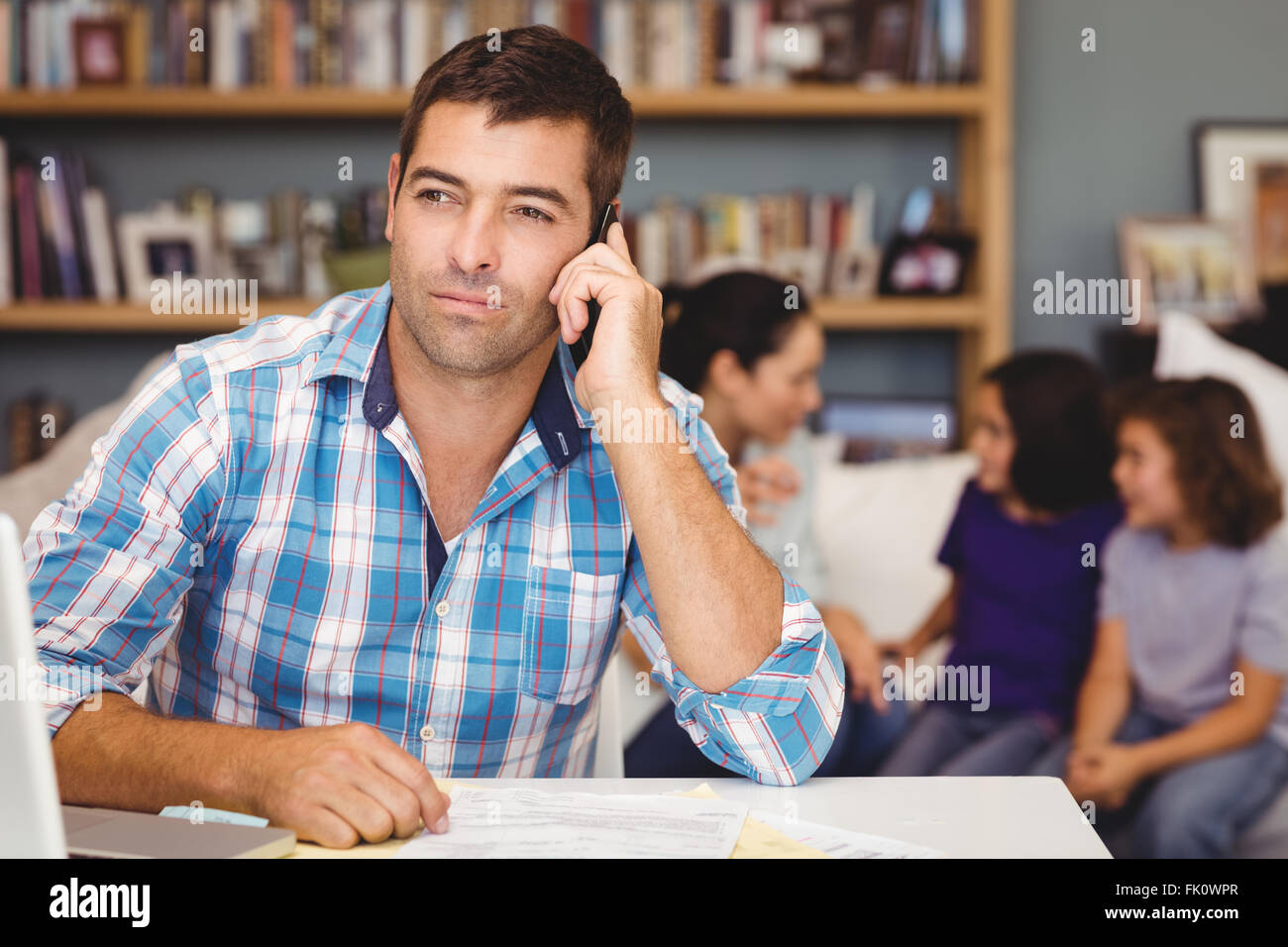 Confident man using mobile phone while family in background Stock Photo ...