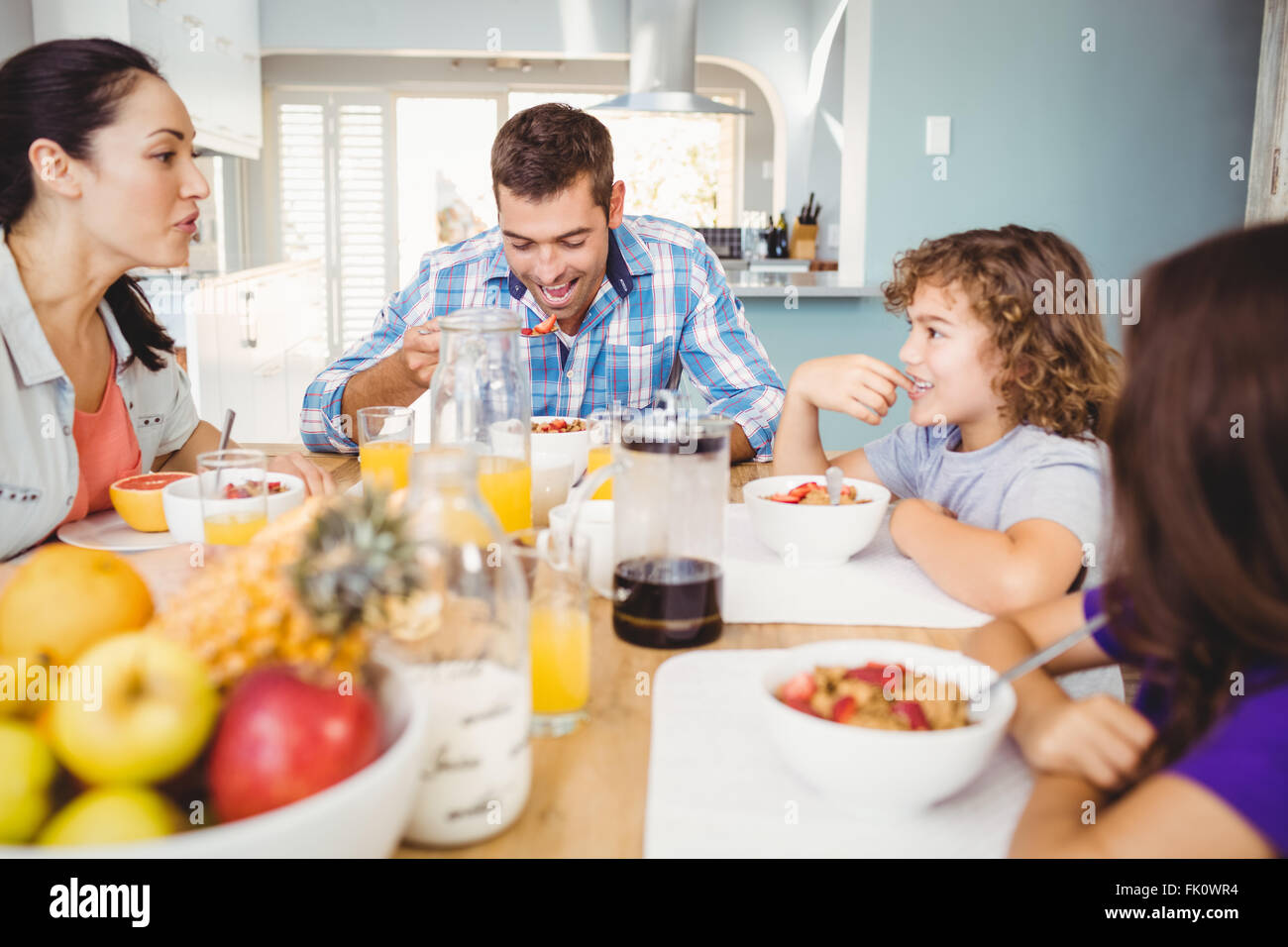 Happy family eating breakfast at table Stock Photo - Alamy