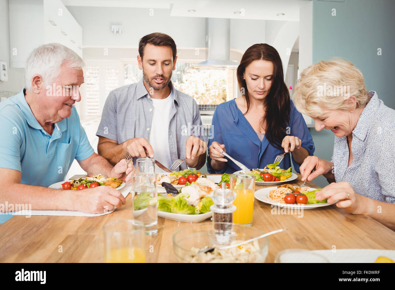 Family sitting at dining table with food Stock Photo - Alamy