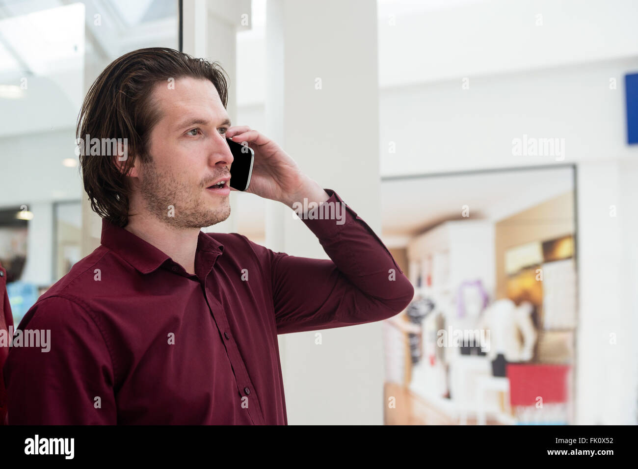 Man talking on mobile phone outside a shop Stock Photo - Alamy