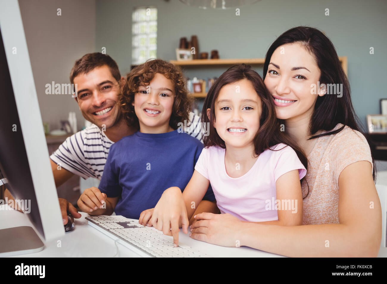 Portrait of happy family sitting by computer Stock Photo - Alamy