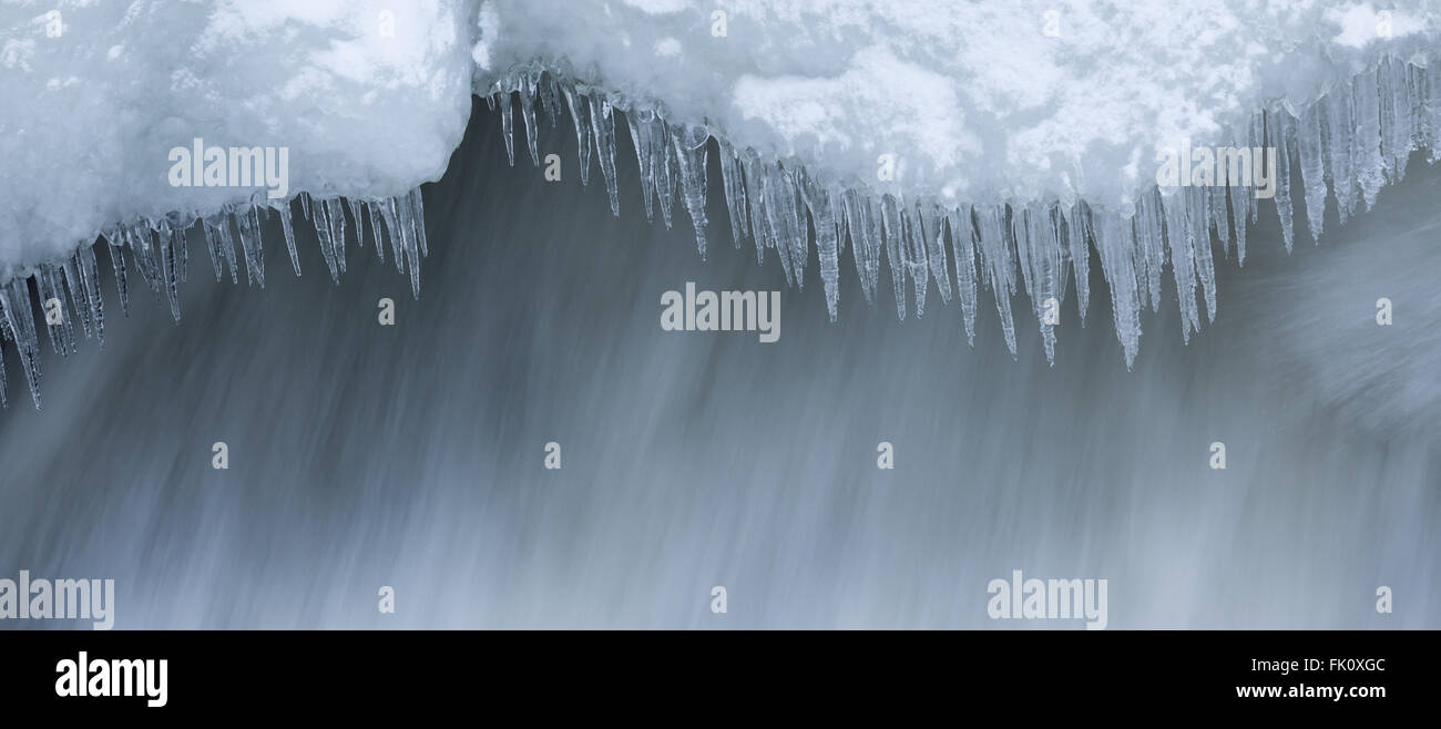 Icicles and snow near flowing water Stock Photo - Alamy