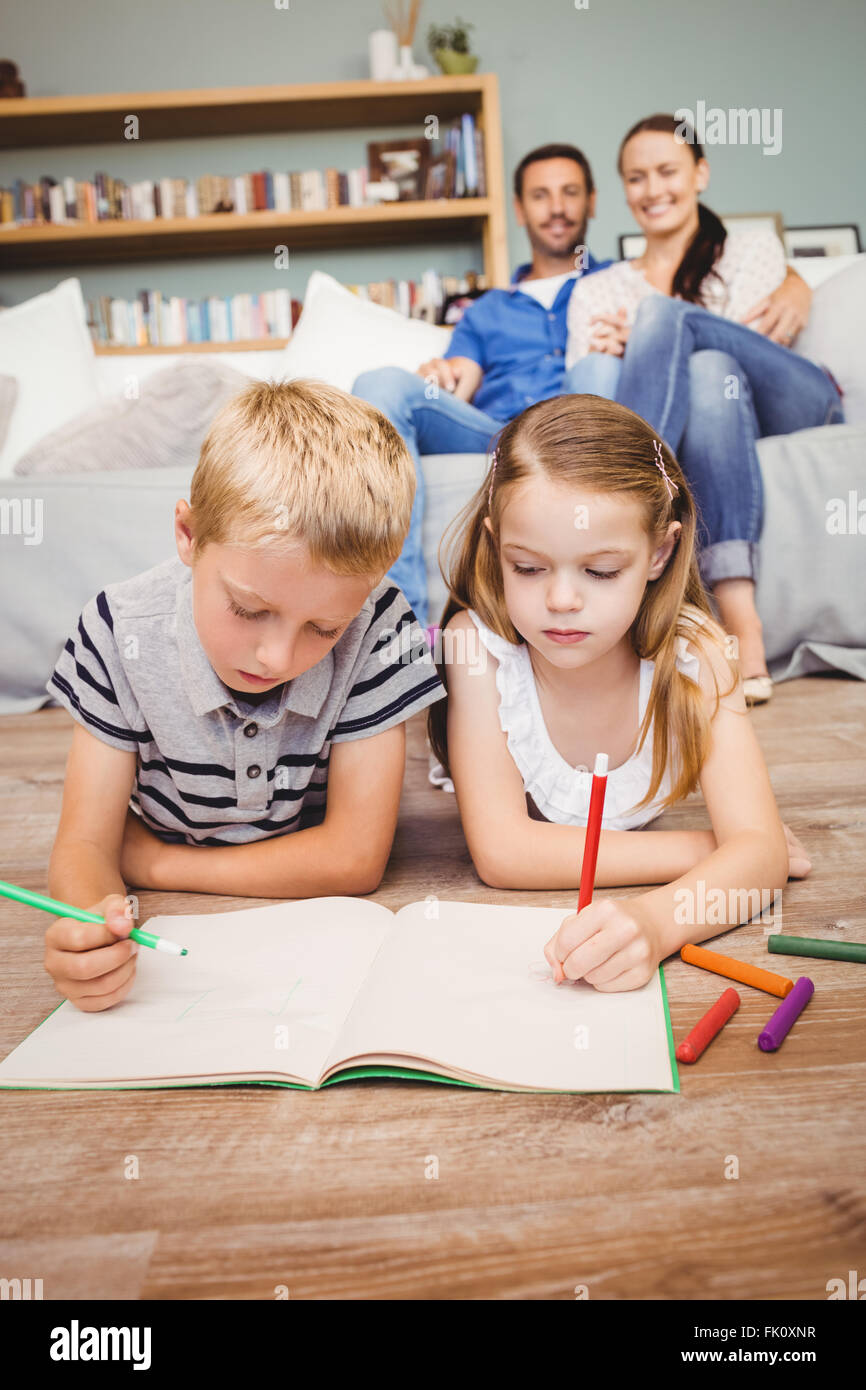 Children drawing on book while parents looking at them Stock Photo - Alamy