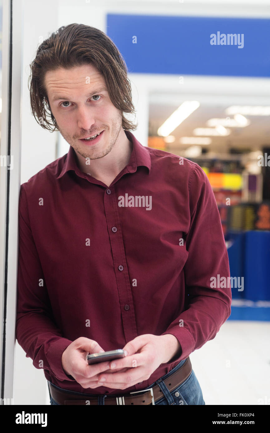 Portrait of man using a mobile phone outside a shop Stock Photo - Alamy