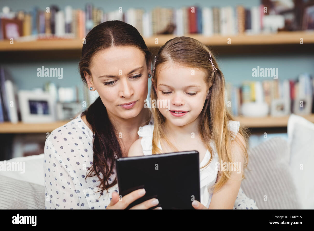 Mother and daughter using digital tablet on sofa at home Stock Photo ...