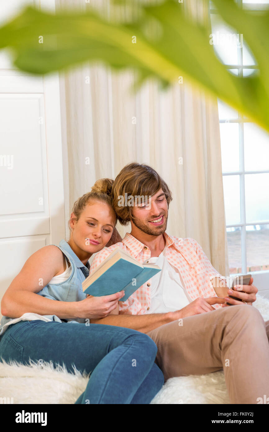 Cute couple reading a book and using smartphone Stock Photo - Alamy
