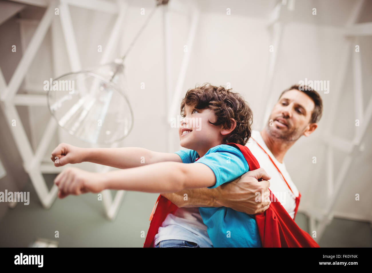 Low angle view of father holding cheerful son wearing superhero costume ...