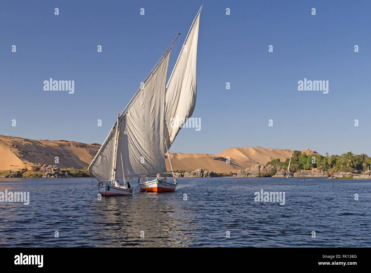 Two Egyptian sailing boats are sailing down the Nile near Aswan city ...