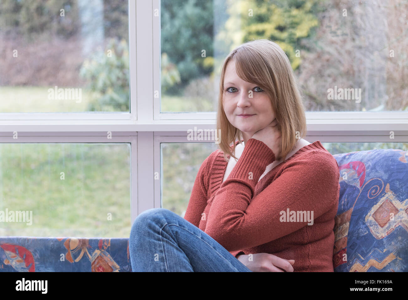 Toothless smiling young woman dressed in a brown sweater is sitting on ...