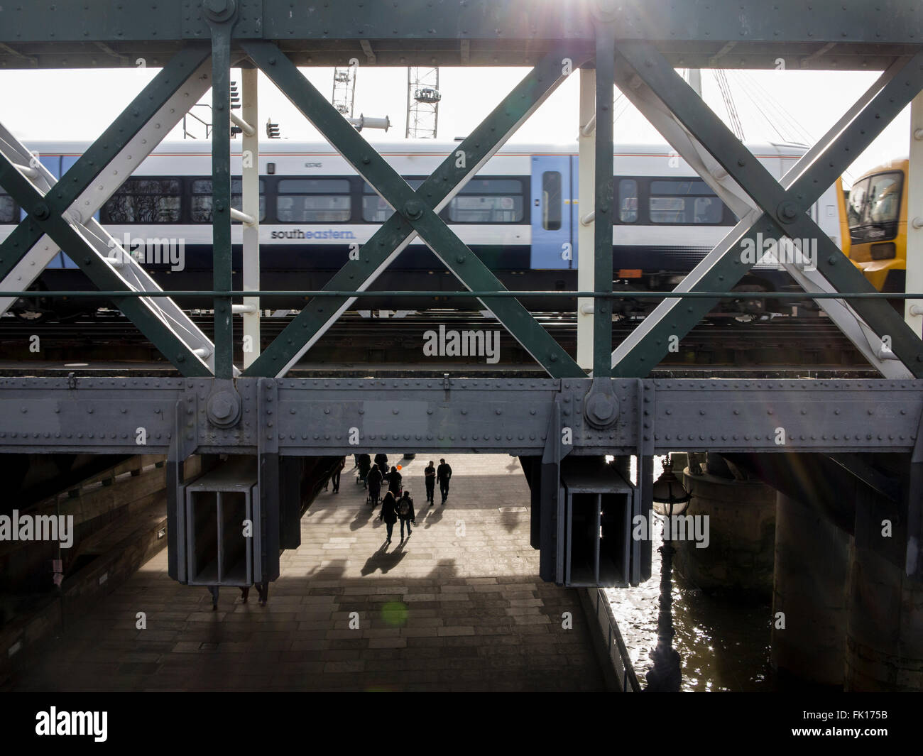 Hungerford railway bridge with a train and commuters below Stock Photo ...