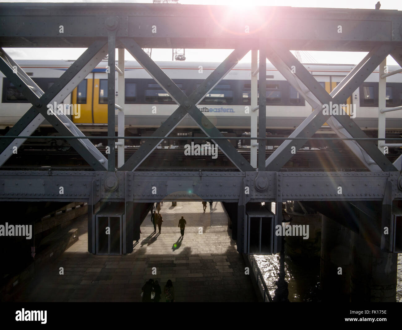 Hungerford railway bridge with a train and commuters below Stock Photo ...